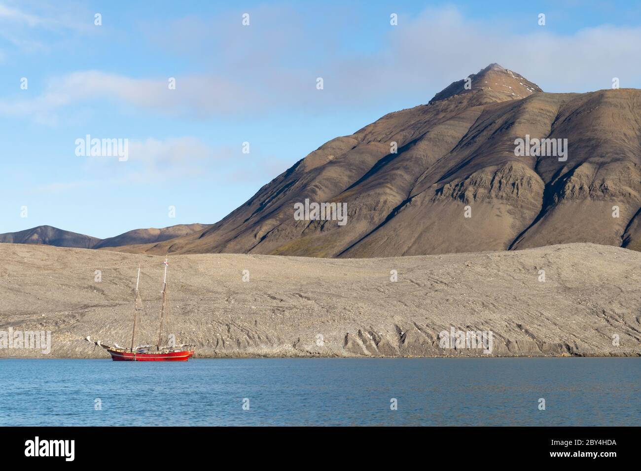 Red sailing ship in front of mountains without vegetation. Summer ...
