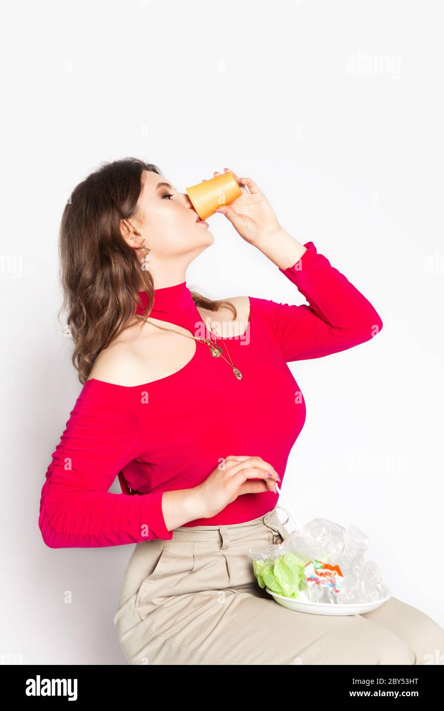 Young beautiful woman eating a plastic bag as a concept of plastic ...