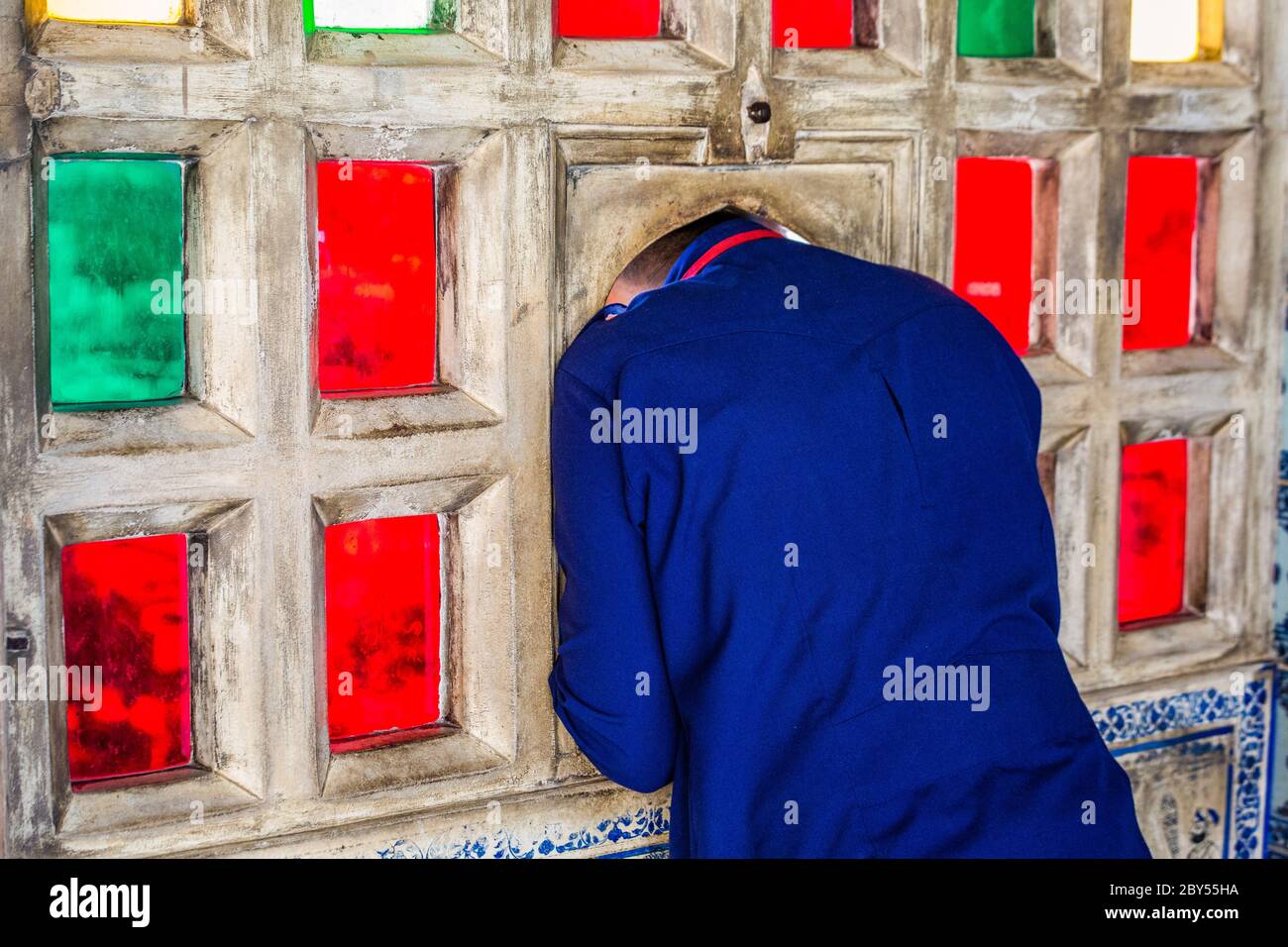 Man looking through stained glass window at Udaipur castle, India Stock ...