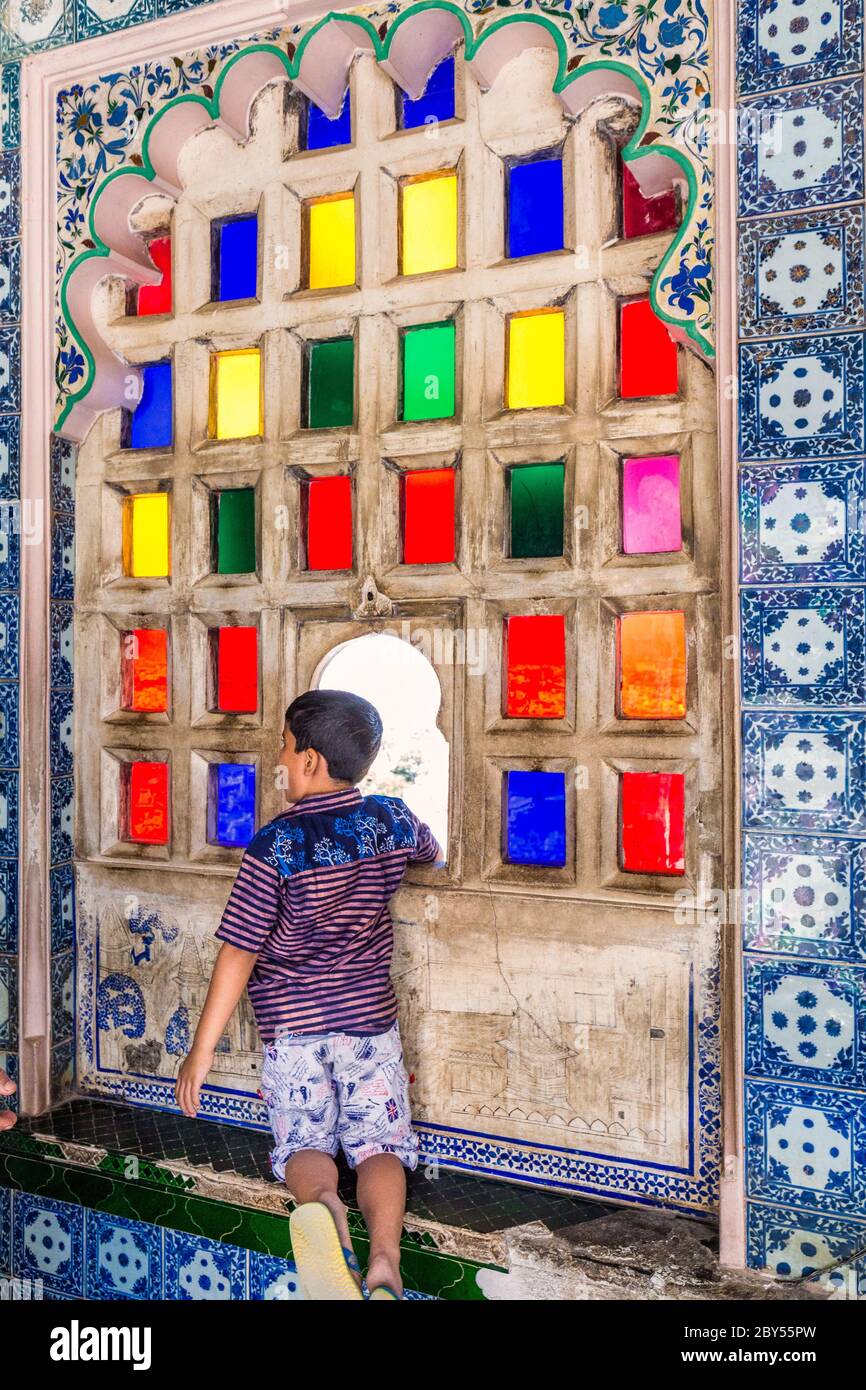 Child looking through stained glass window at Udaipur castle, India ...