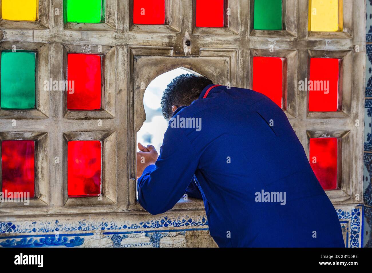 Man looking through stained glass window at Udaipur castle, India Stock ...