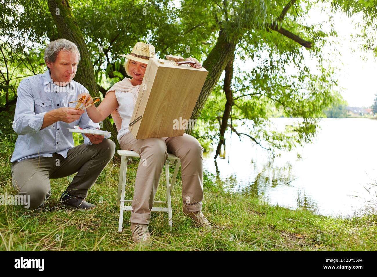 Painter and assistant painting a picture in summer Stock Photo - Alamy