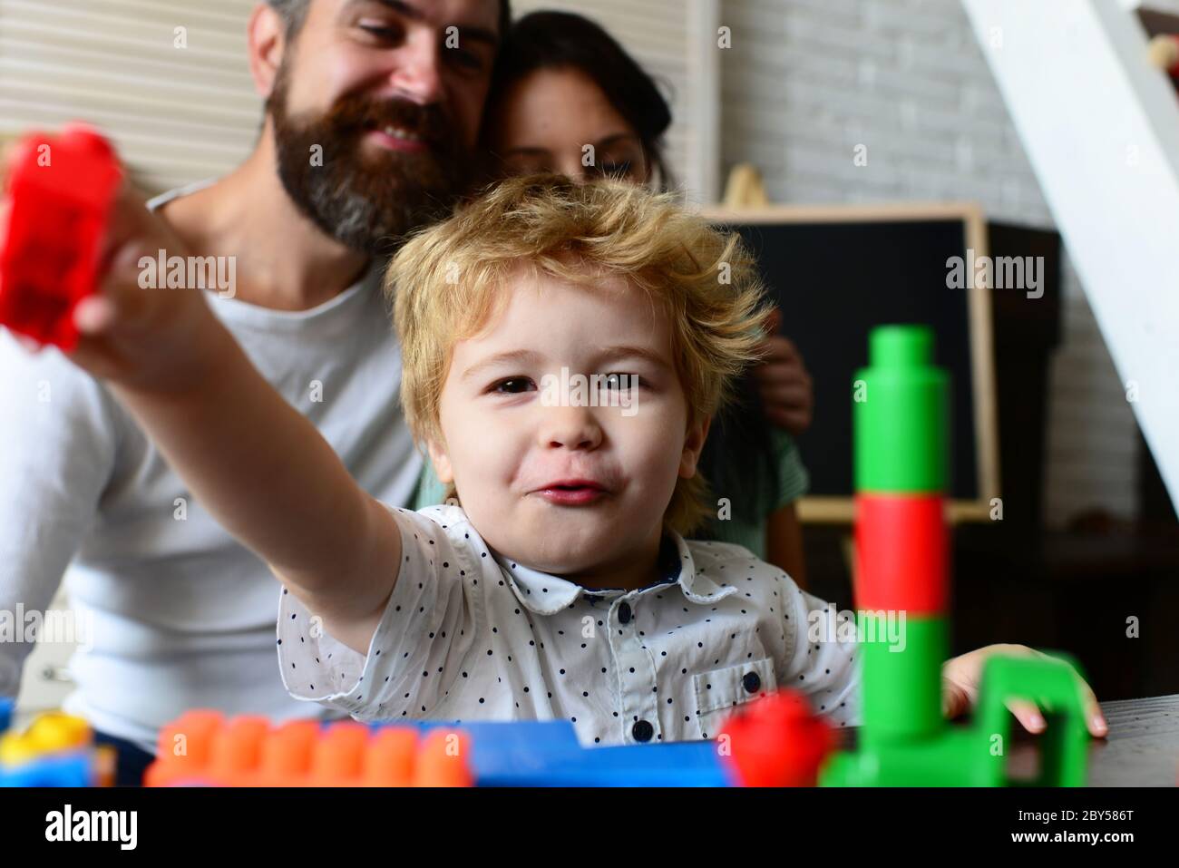 Boy builds out of plastic blocks on light background, defocused. Love ...