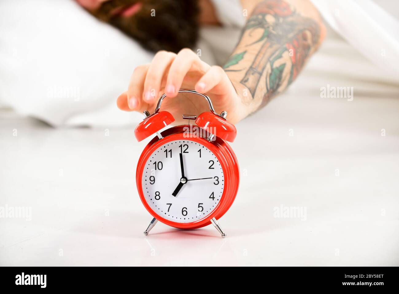 Male hand with tattoo try to turn off annoying alarm clock, white ...