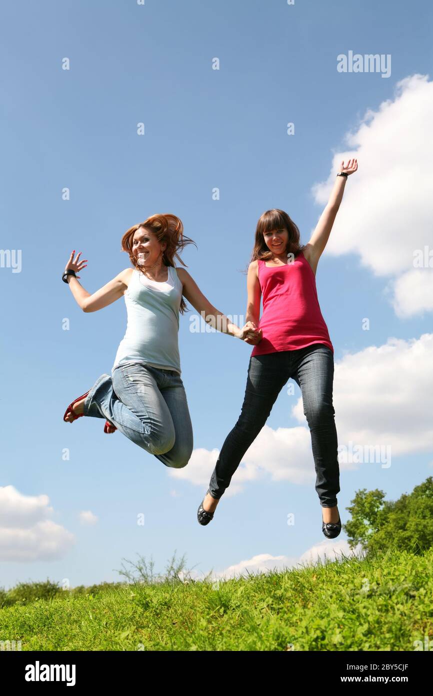 two girls jump under blue sky Stock Photo - Alamy