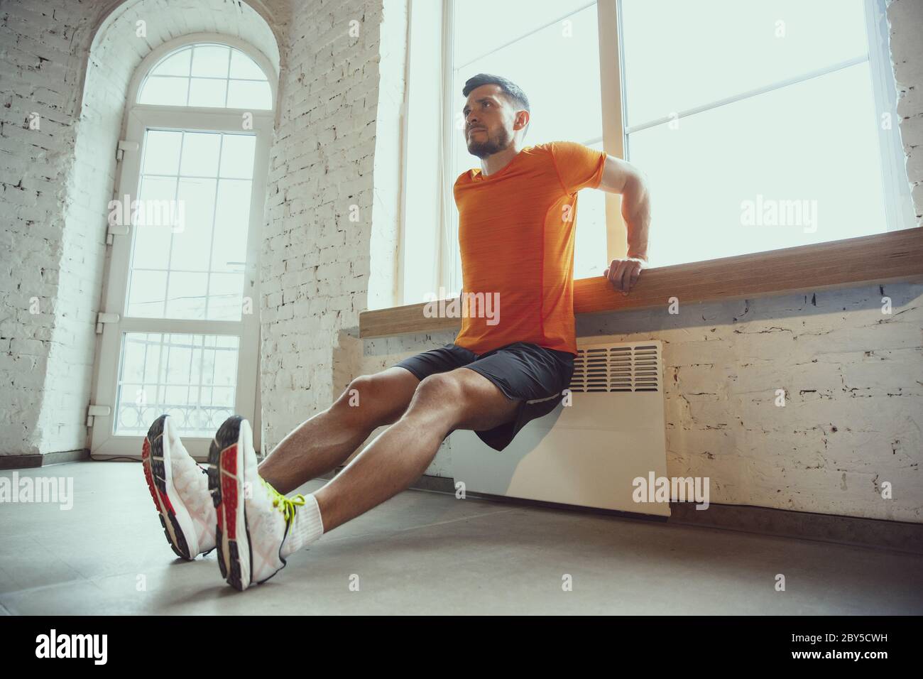 Sit ups. Young caucasian man training at home during quarantine of ...