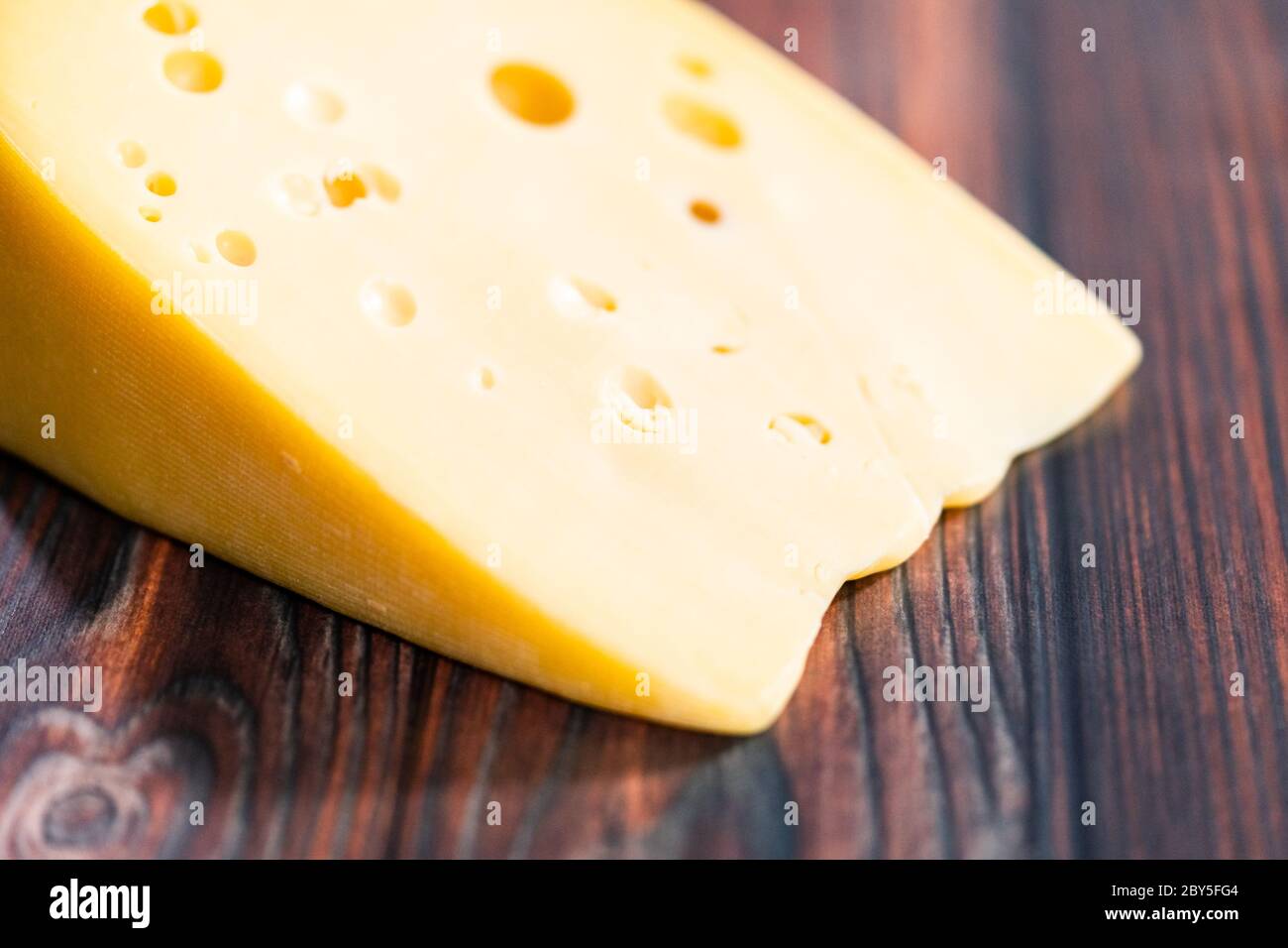 Large wedge of semi soft part-skim swiss cheese on a dark wooden background Stock Photo - Alamy