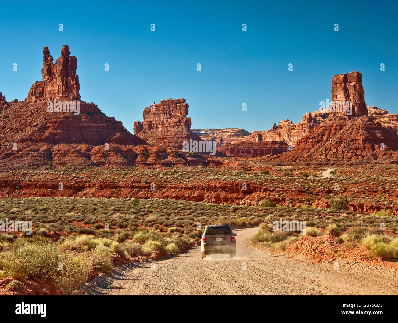 Car on dirt road, sandstone rock formations at Valley of the Gods ...