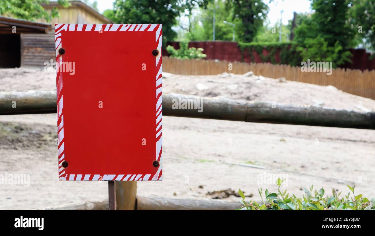 Red blank metallic signboard on a fence for artwork template design ...