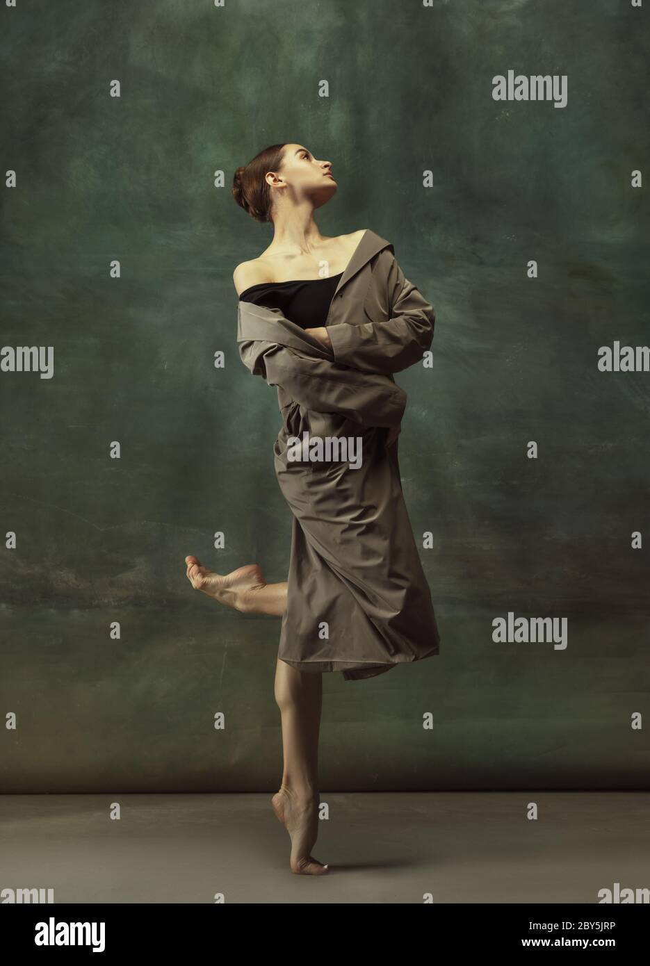 Warm. Graceful classic ballerina dancing, posing isolated on dark ...