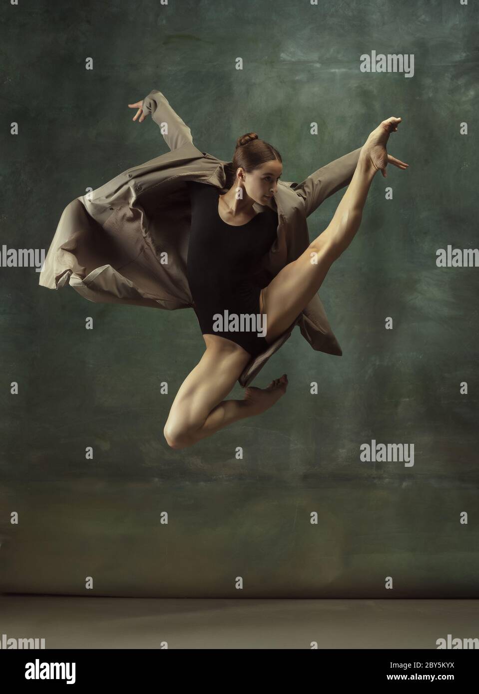 In flight. Graceful classic ballerina dancing, posing isolated on dark ...