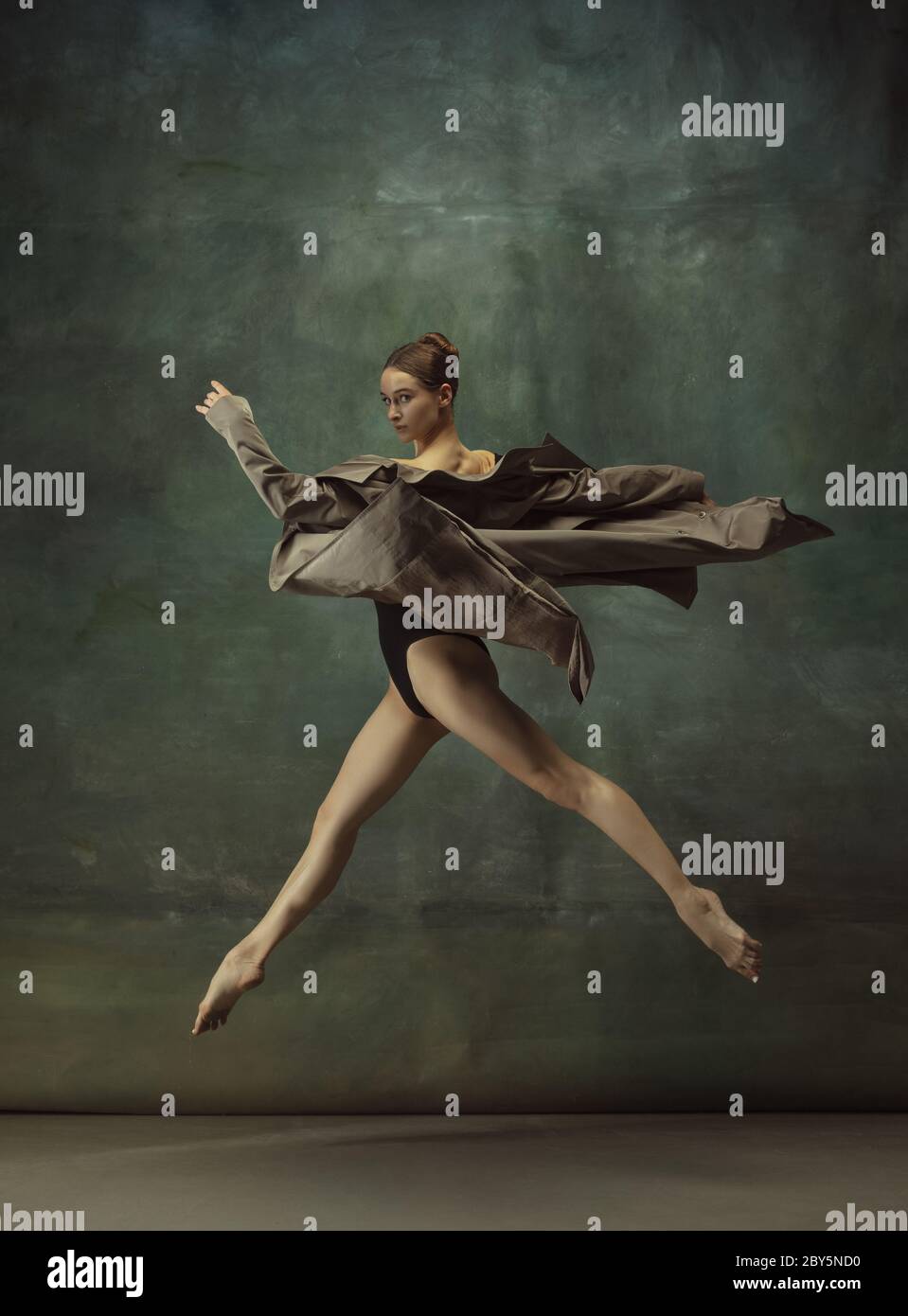 In flight. Graceful classic ballerina dancing, posing isolated on dark ...