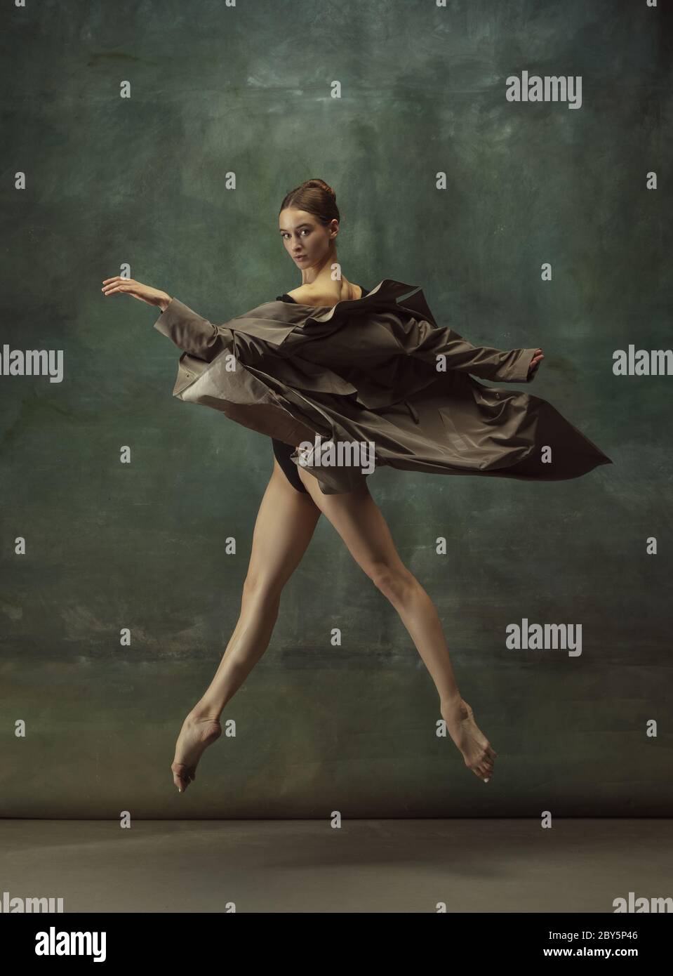 In flight. Graceful classic ballerina dancing, posing isolated on dark ...