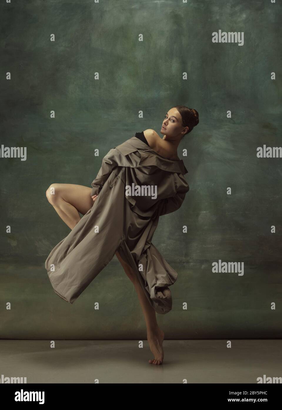 Warm. Graceful classic ballerina dancing, posing isolated on dark ...