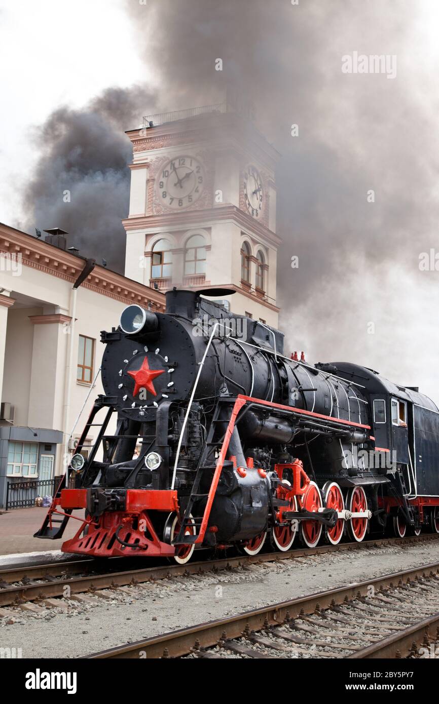 Old steam train is leaving a station Stock Photo - Alamy