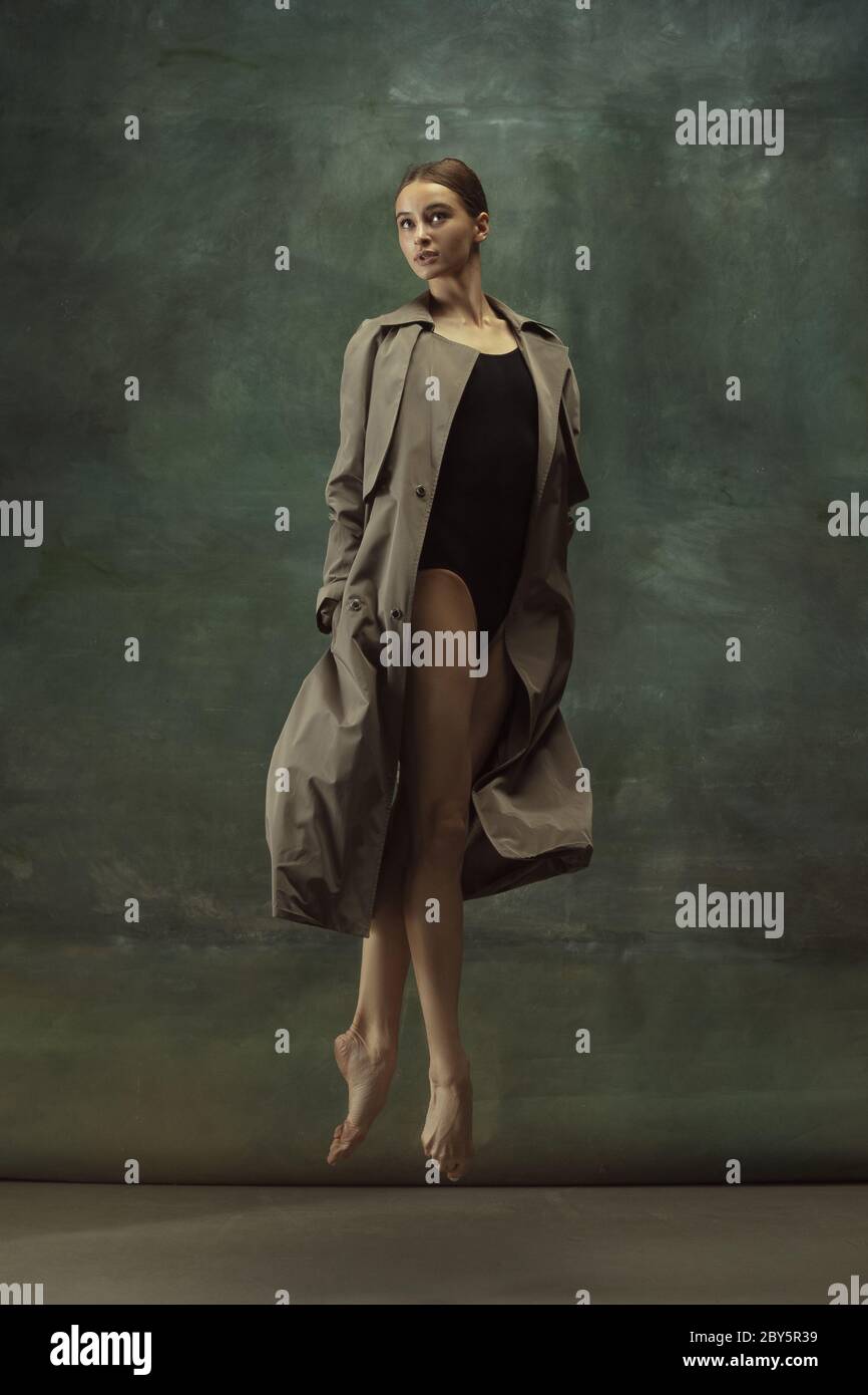 In flight. Graceful classic ballerina dancing, posing isolated on dark ...