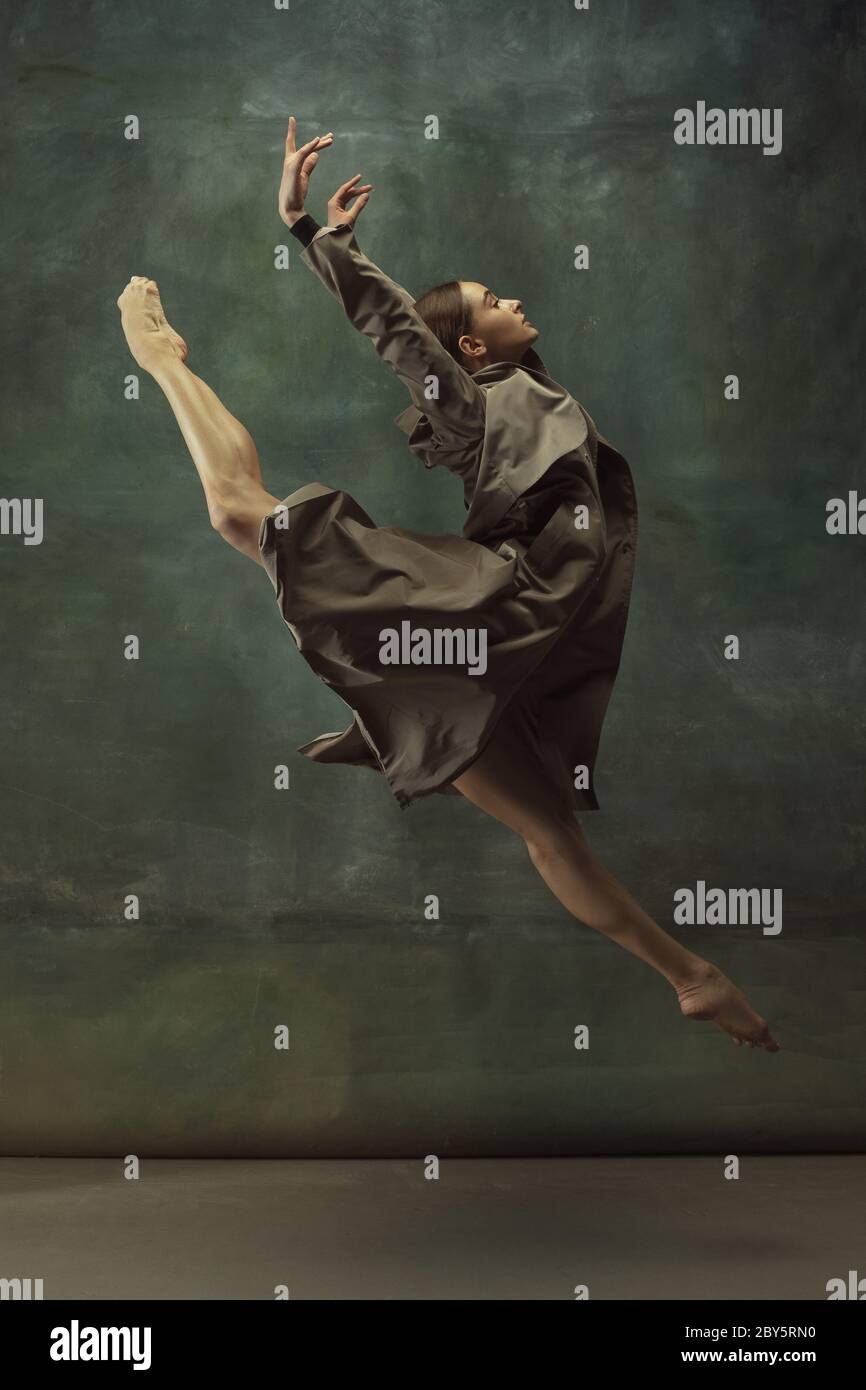 In flight. Graceful classic ballerina dancing, posing isolated on dark ...