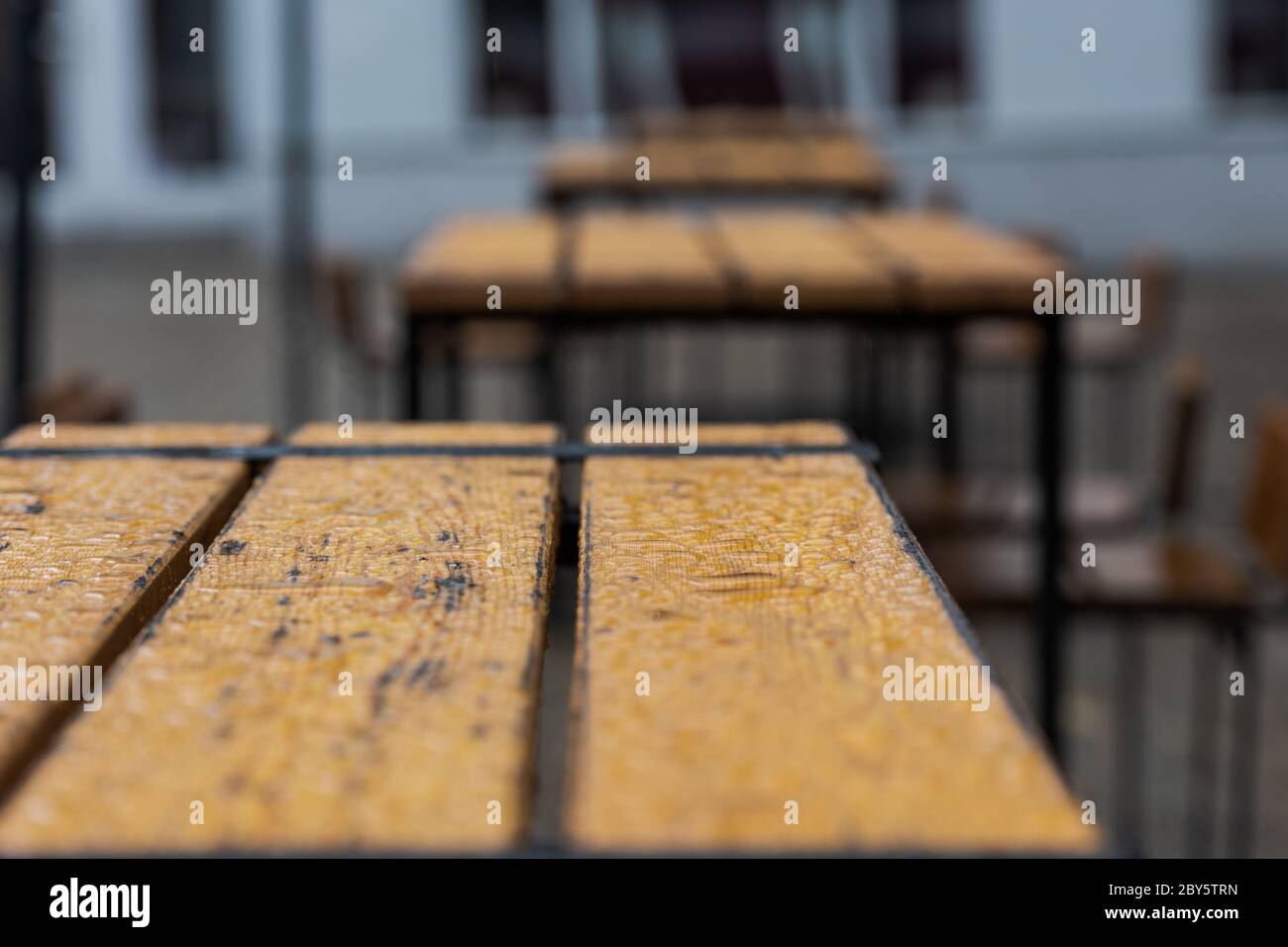 Empty and wet vintage wooden tables and chairs of closed outdoor ...