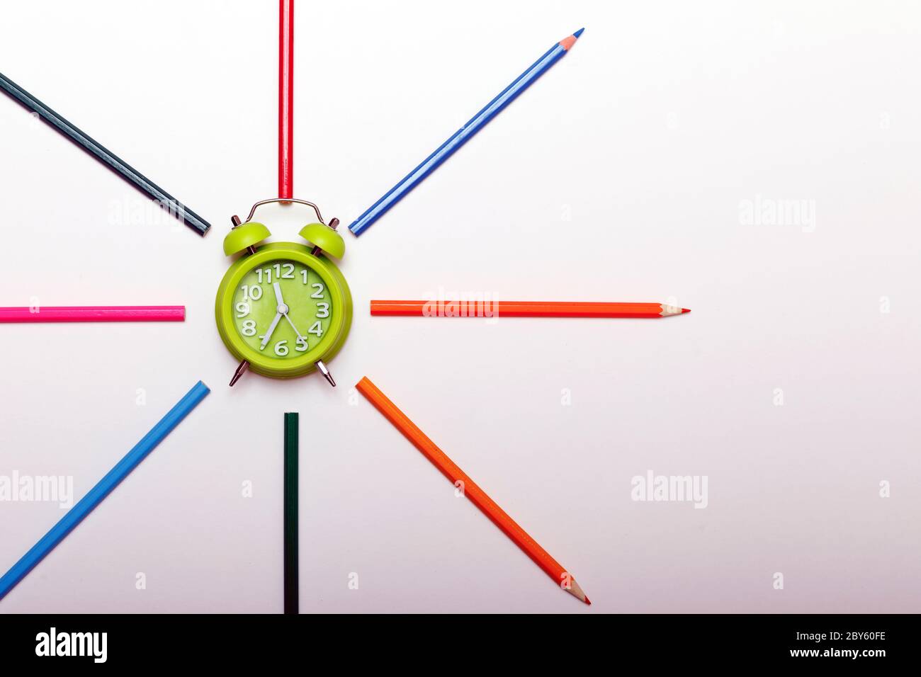 Alarm clock with color pencils around on white background Stock Photo ...
