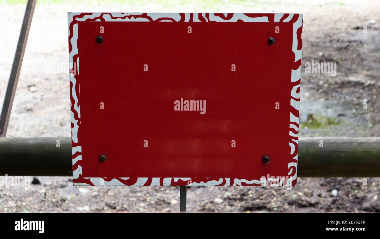 Red blank metallic signboard on a fence for artwork template design ...