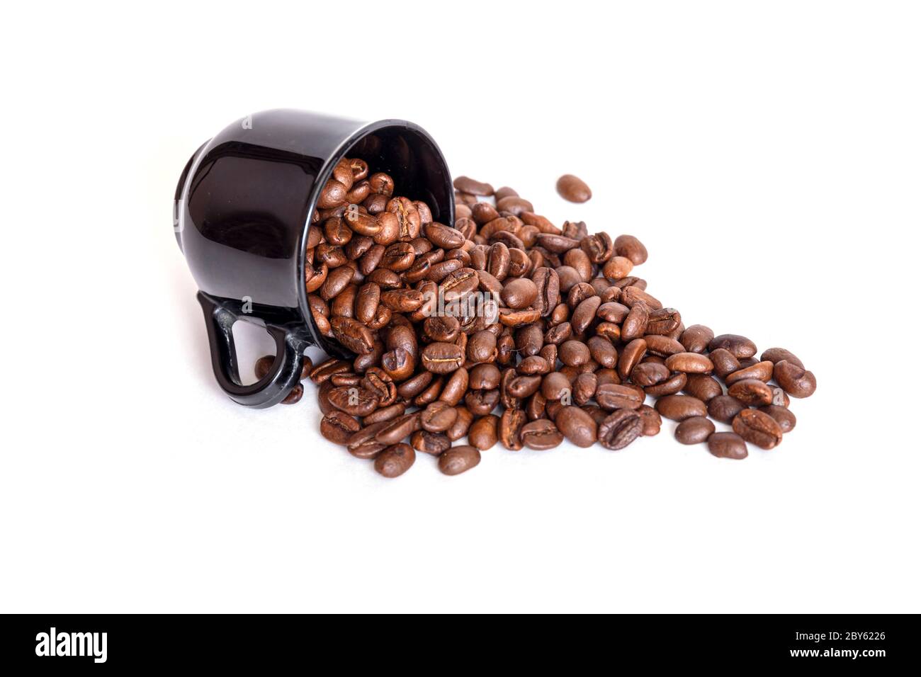 Spilled coffee beans from the black ceramic cup isolated on white ...