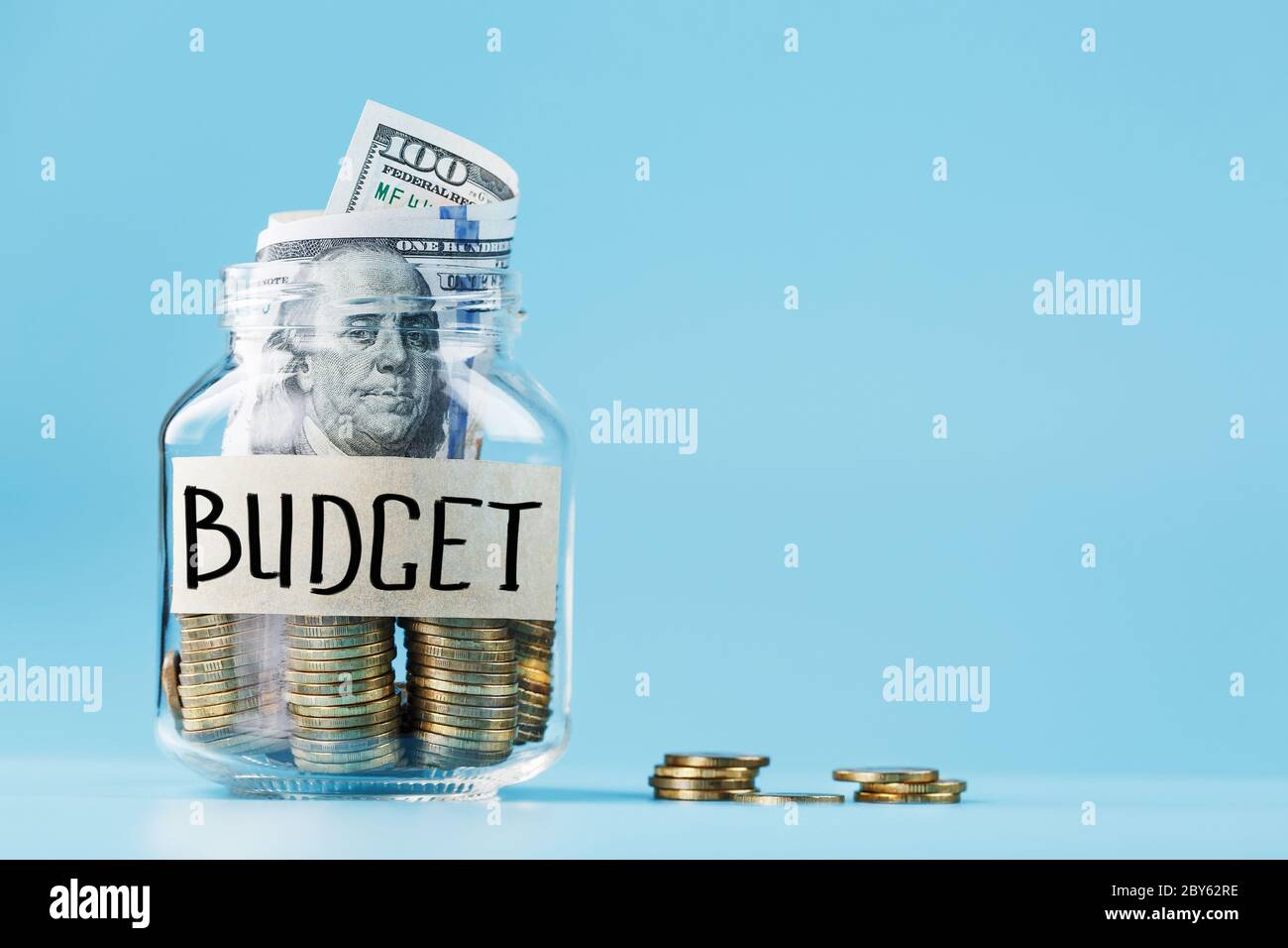 Glass jar with coins and dollars, with a sticker saying Budget, on a ...