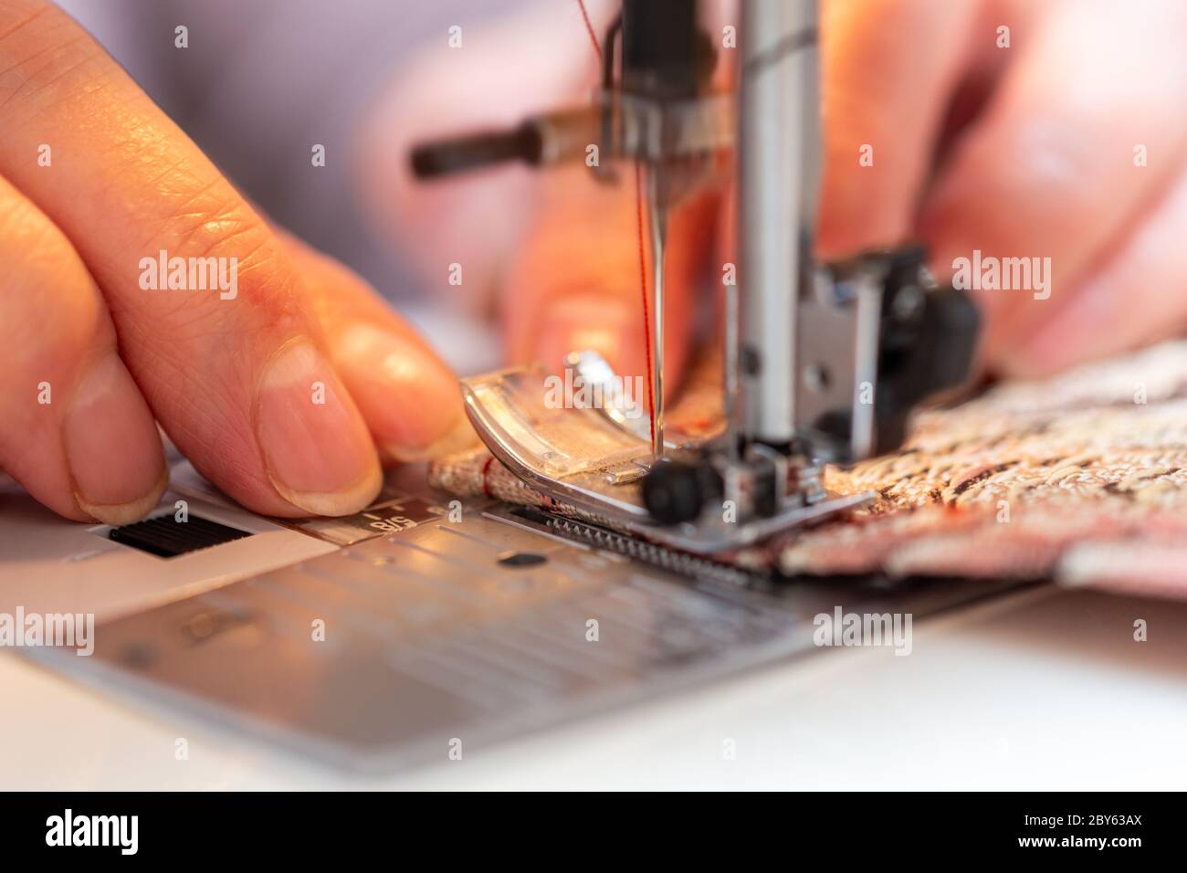 a close-up view of sewing process, hand of old woman using sewing ...
