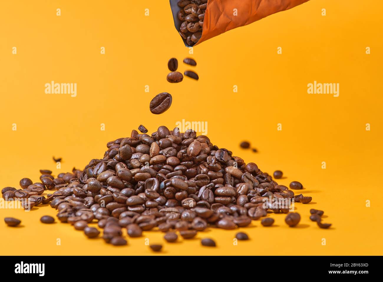 coffee beans falling on a yellow background. Contrasting colors ...