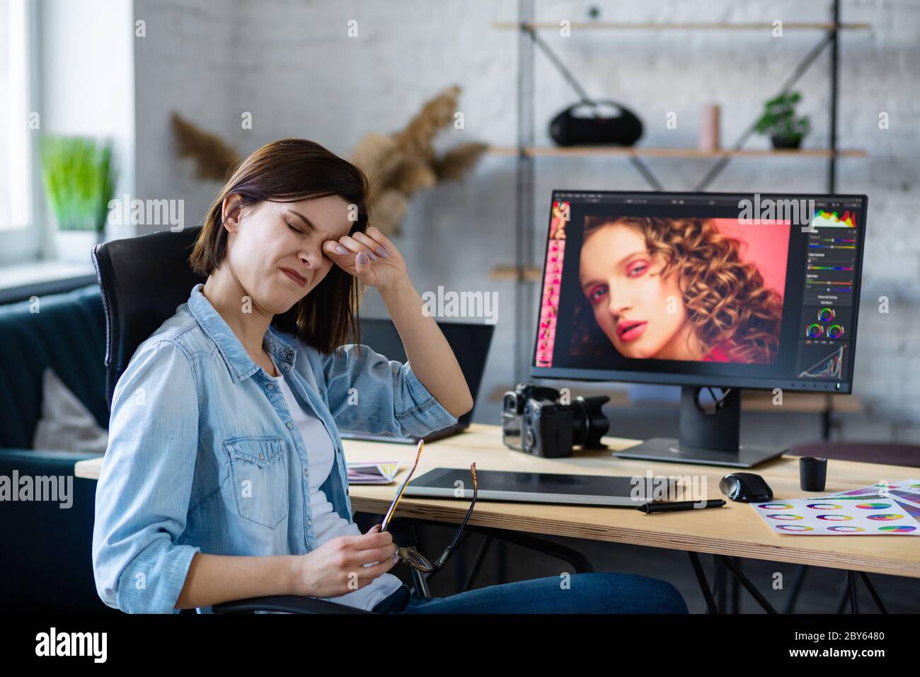 Portrait of tired graphic designer working overtime in office. Stressed ...