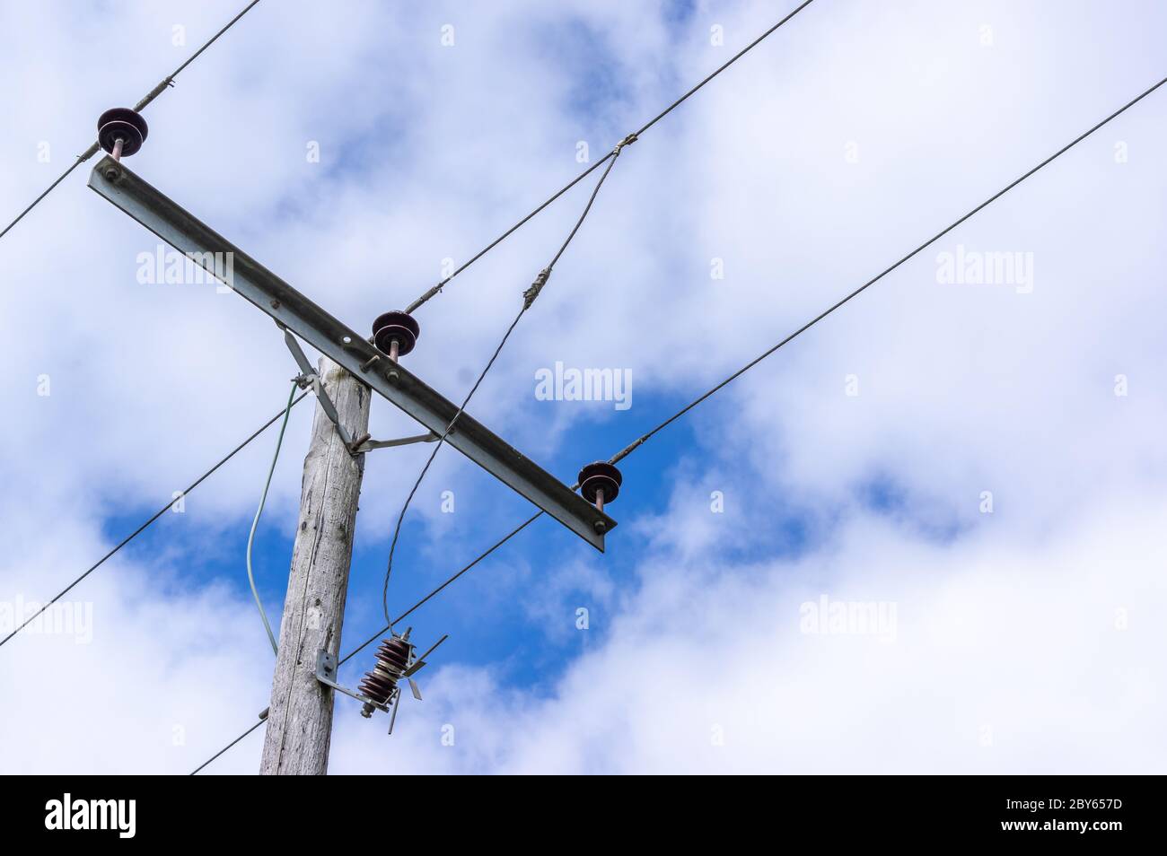 Wooden telegraph pole style power line with 3 wires with a cloudy sky ...