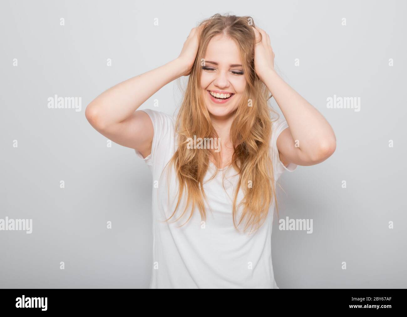 Pretty toothy laughing young woman with fair blond long hair in casual ...