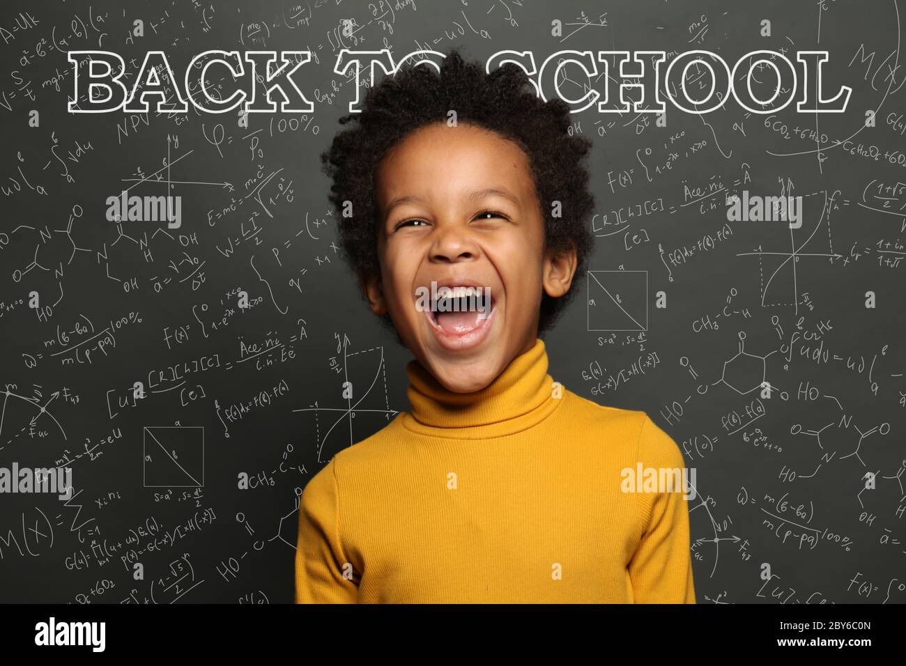Happy black child screaming Back to school! on chalkboard background ...
