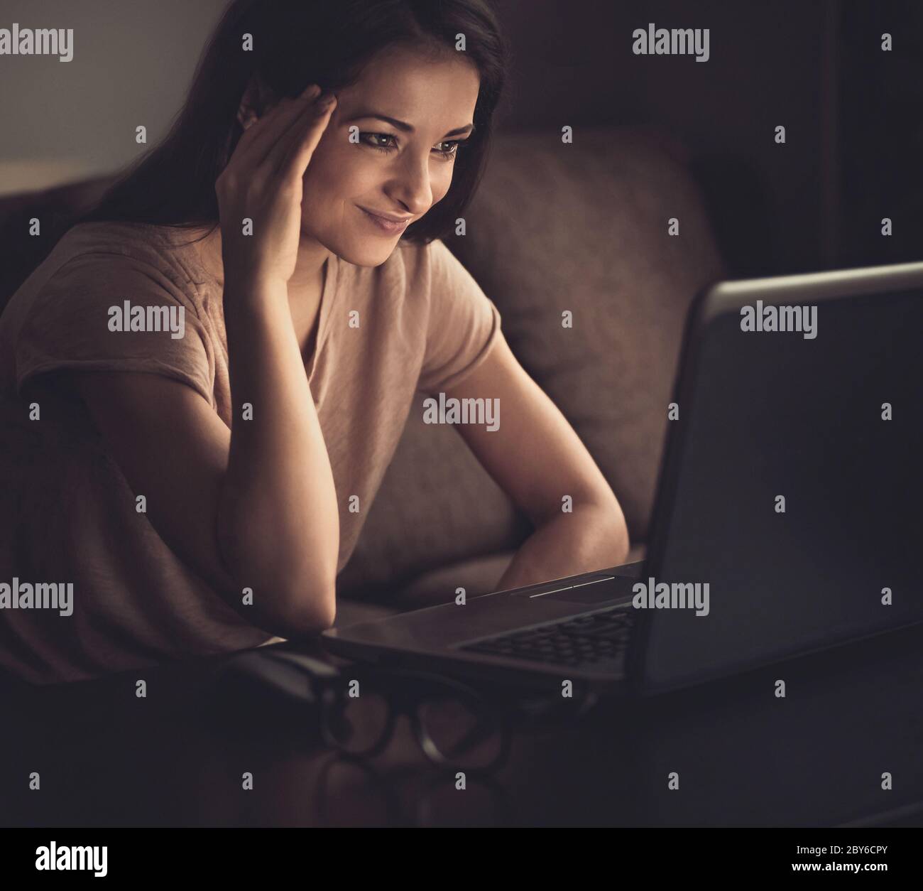 Smiling thinking young beautiful woman looking on computer monitor and ...