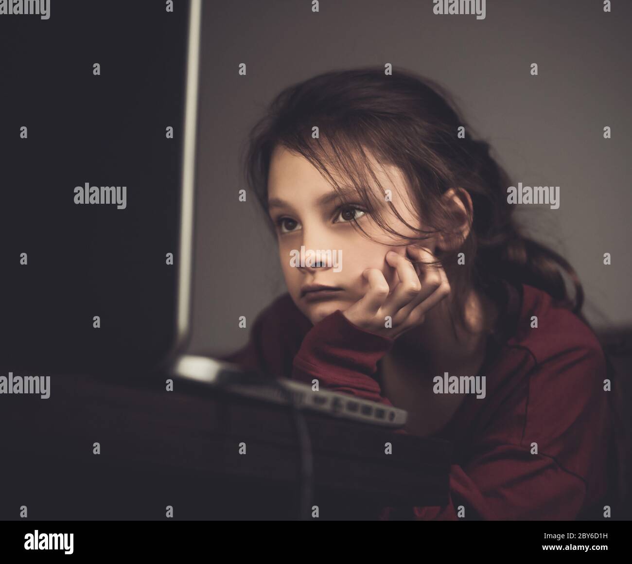 Unhappy thinking kid girl looking on computer monitor at home. Closeup ...