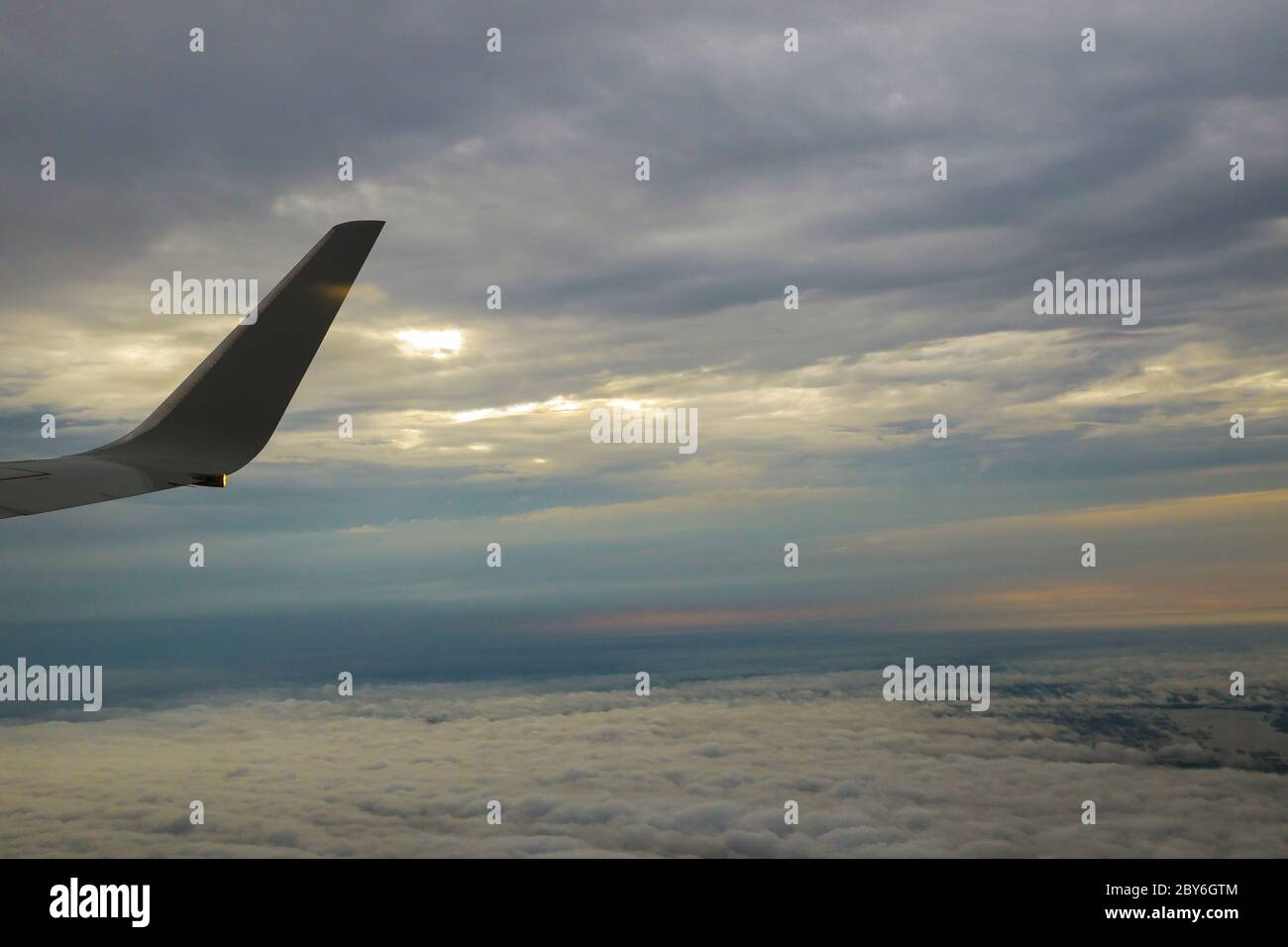 Wing of an airplane flying above the morning clouds in altitude during ...