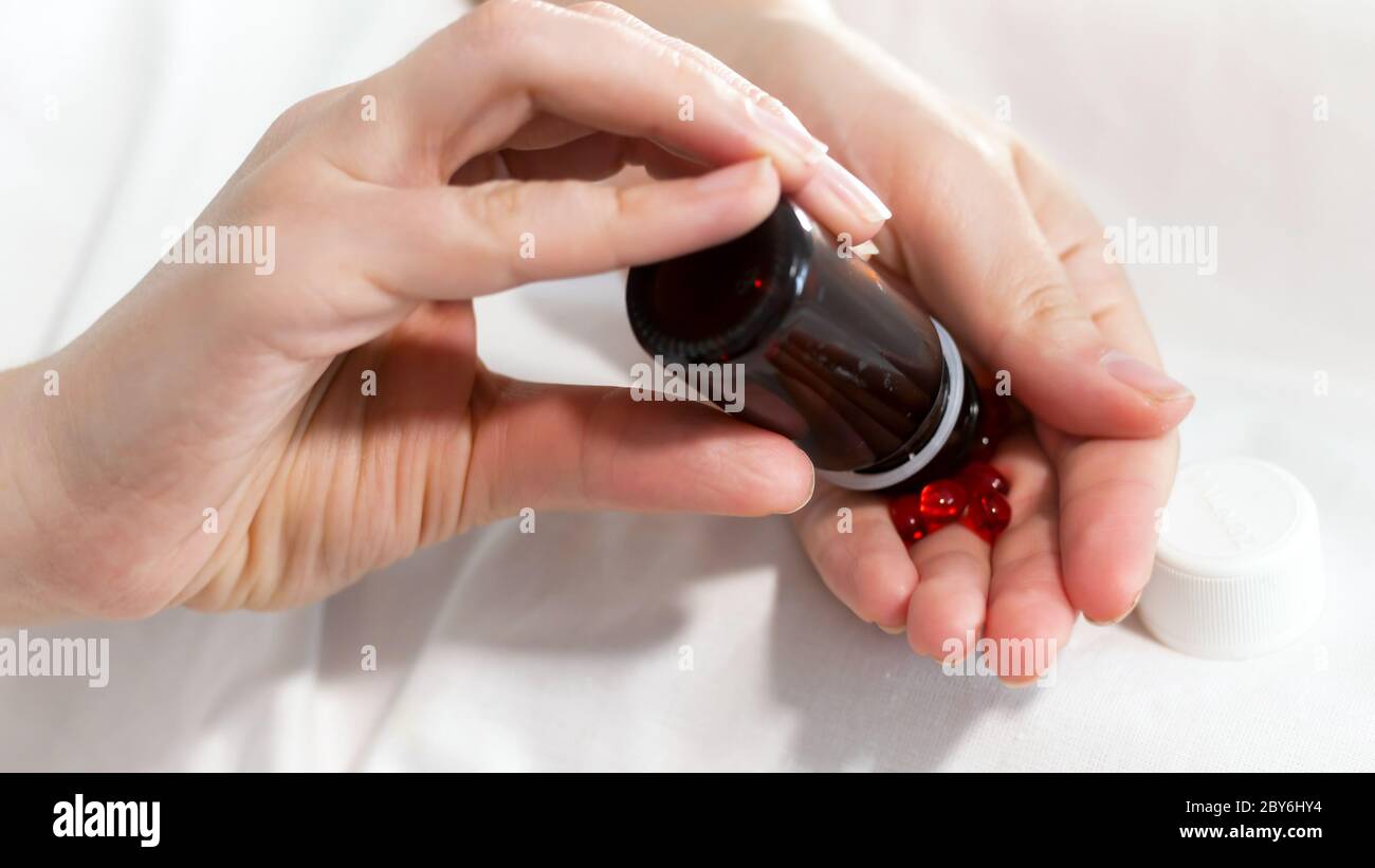 Sick woman pouring pills and tablets on hand from glass bottle Stock ...
