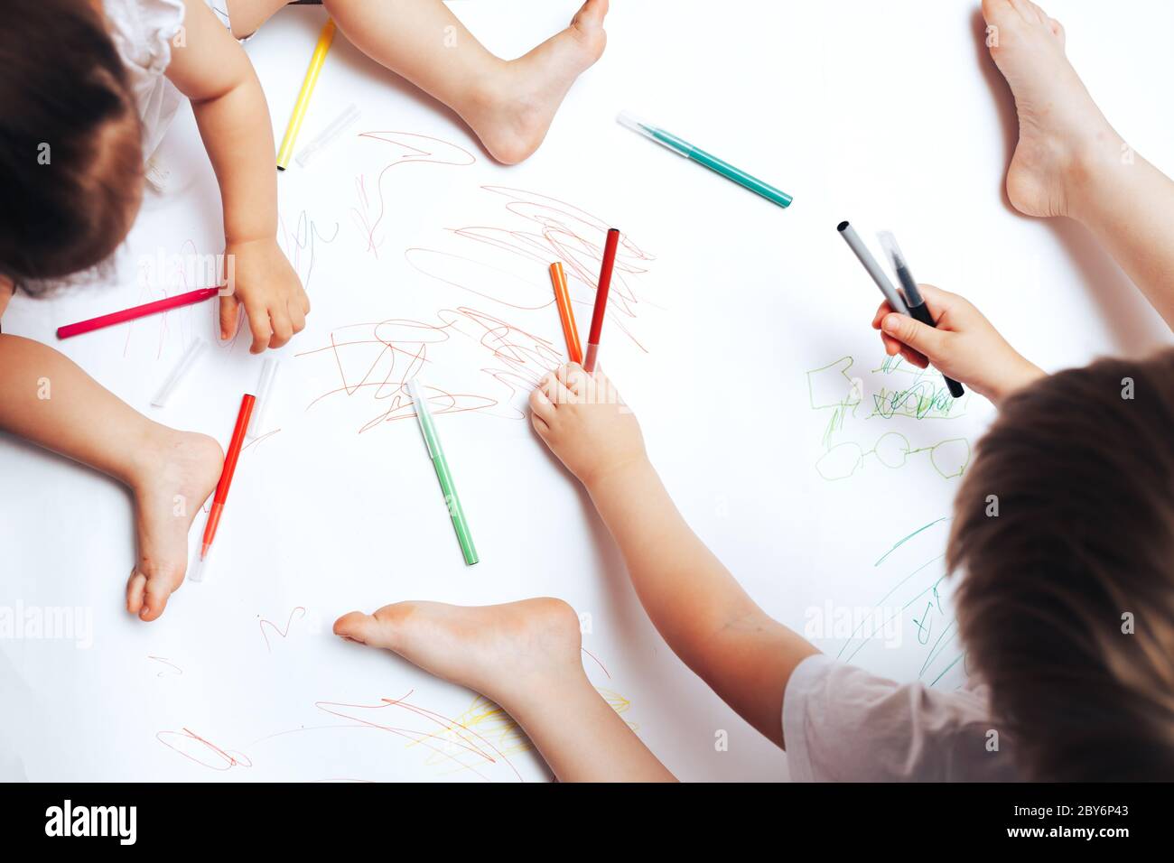 Talented children draw with colored felt-tip pens on white paper ...