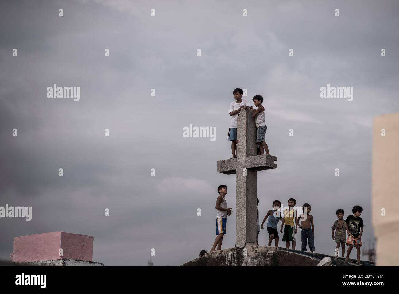 Children stand by a cross from a mausoleum at Navotas cemetery in ...
