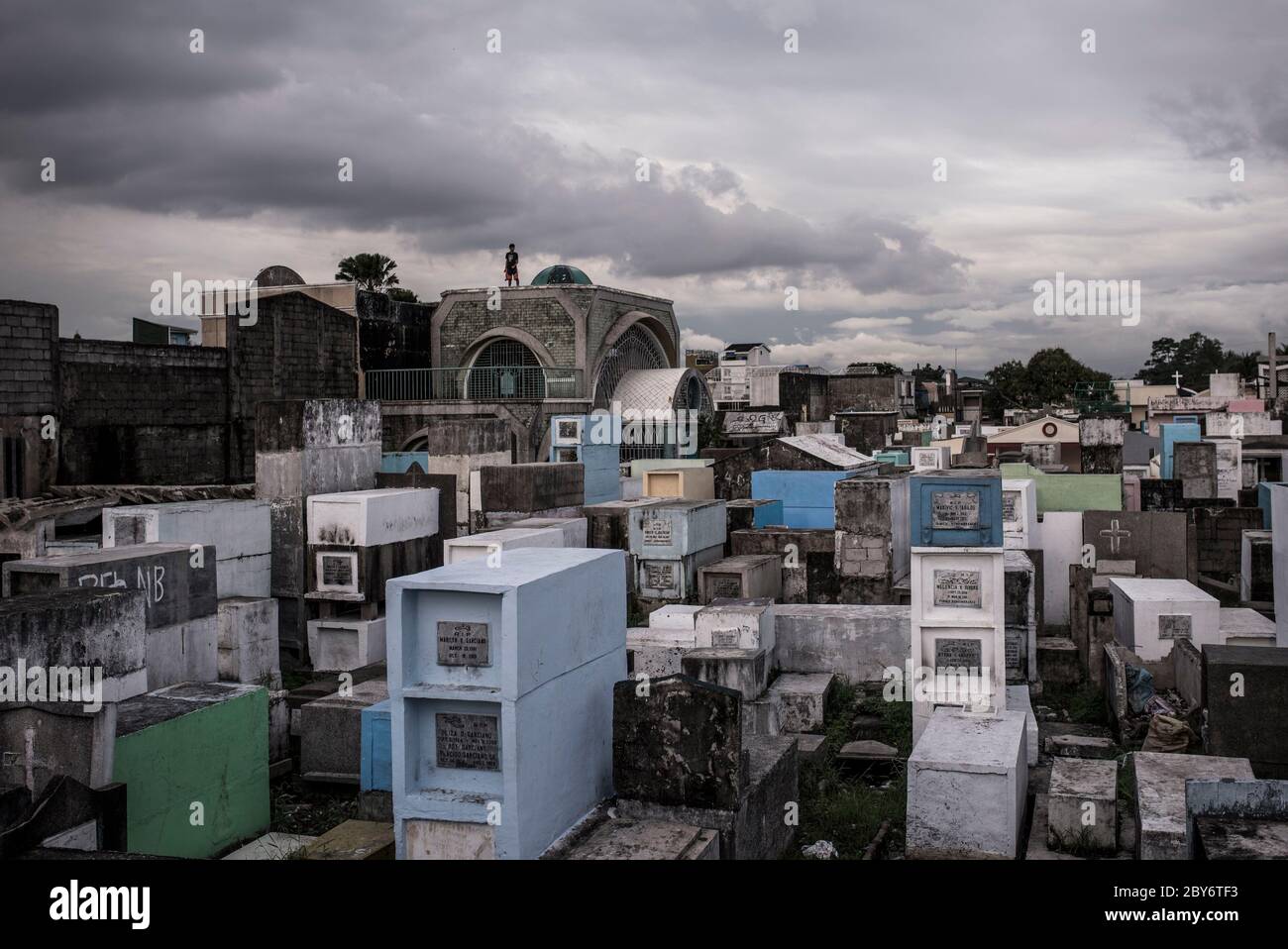A child stands in the distance on top of some graves at Navotas ...