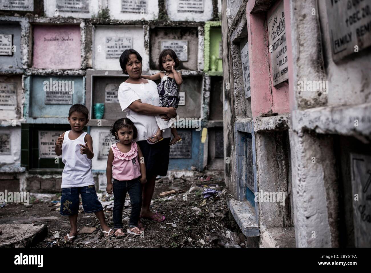 A family poses in fornt of some graves at Navotas cemetery in Manila ...