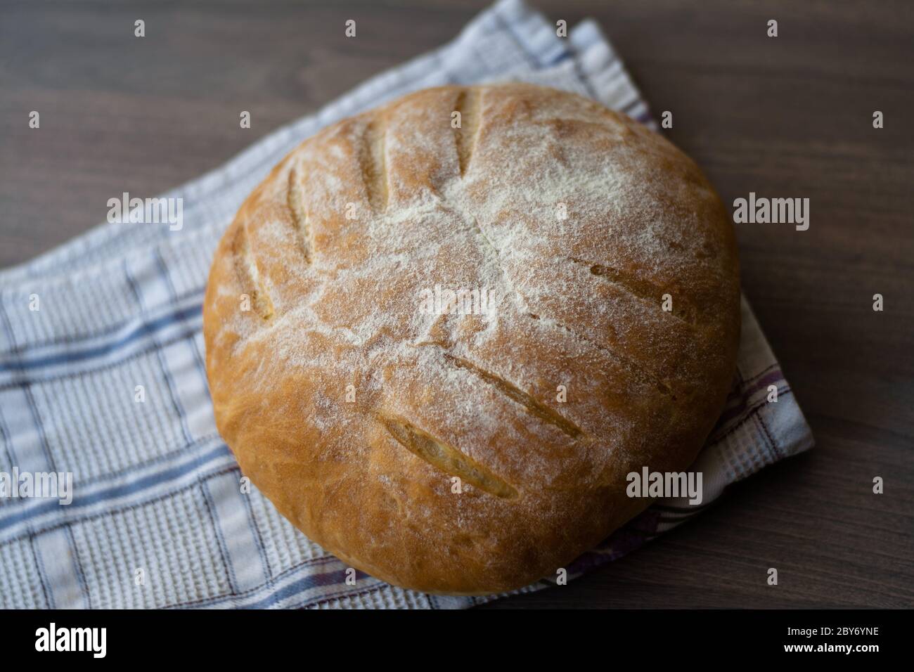 Round sourdough homemade bread with leaf scoring pattern on wooden ...