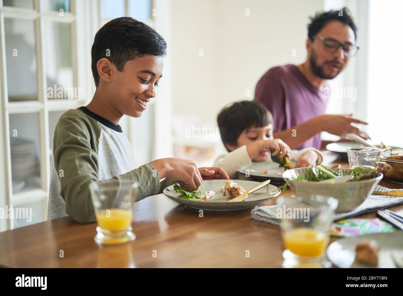 Smiling boy eating dinner with family at table Stock Photo - Alamy