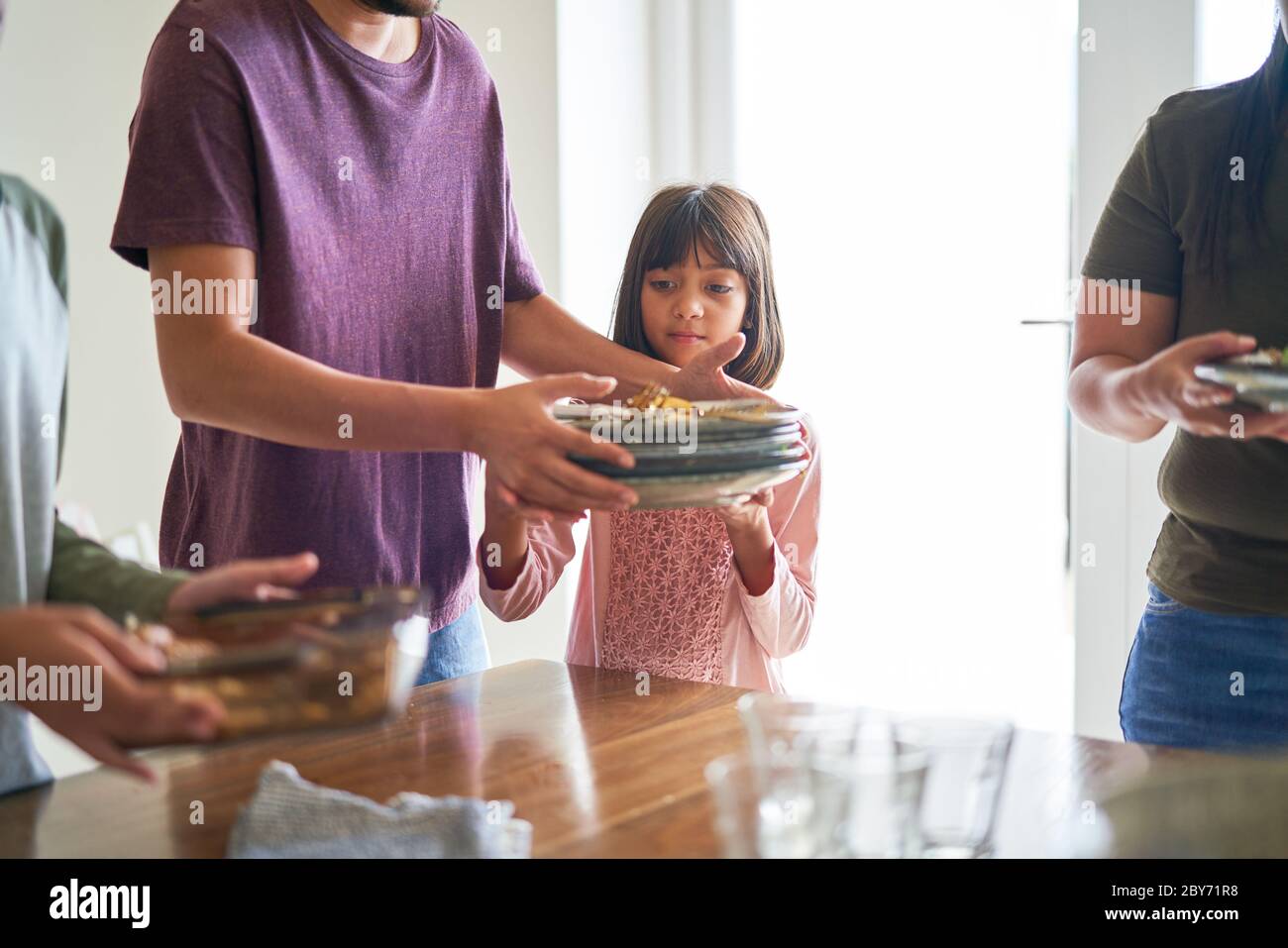 Family clearing dishes from dining table Stock Photo - Alamy