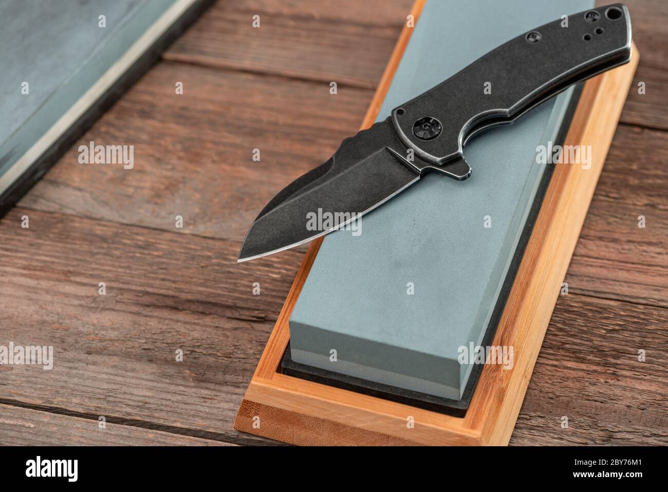 Steel pocket knife and whetstone on a rustic wooden background Stock ...