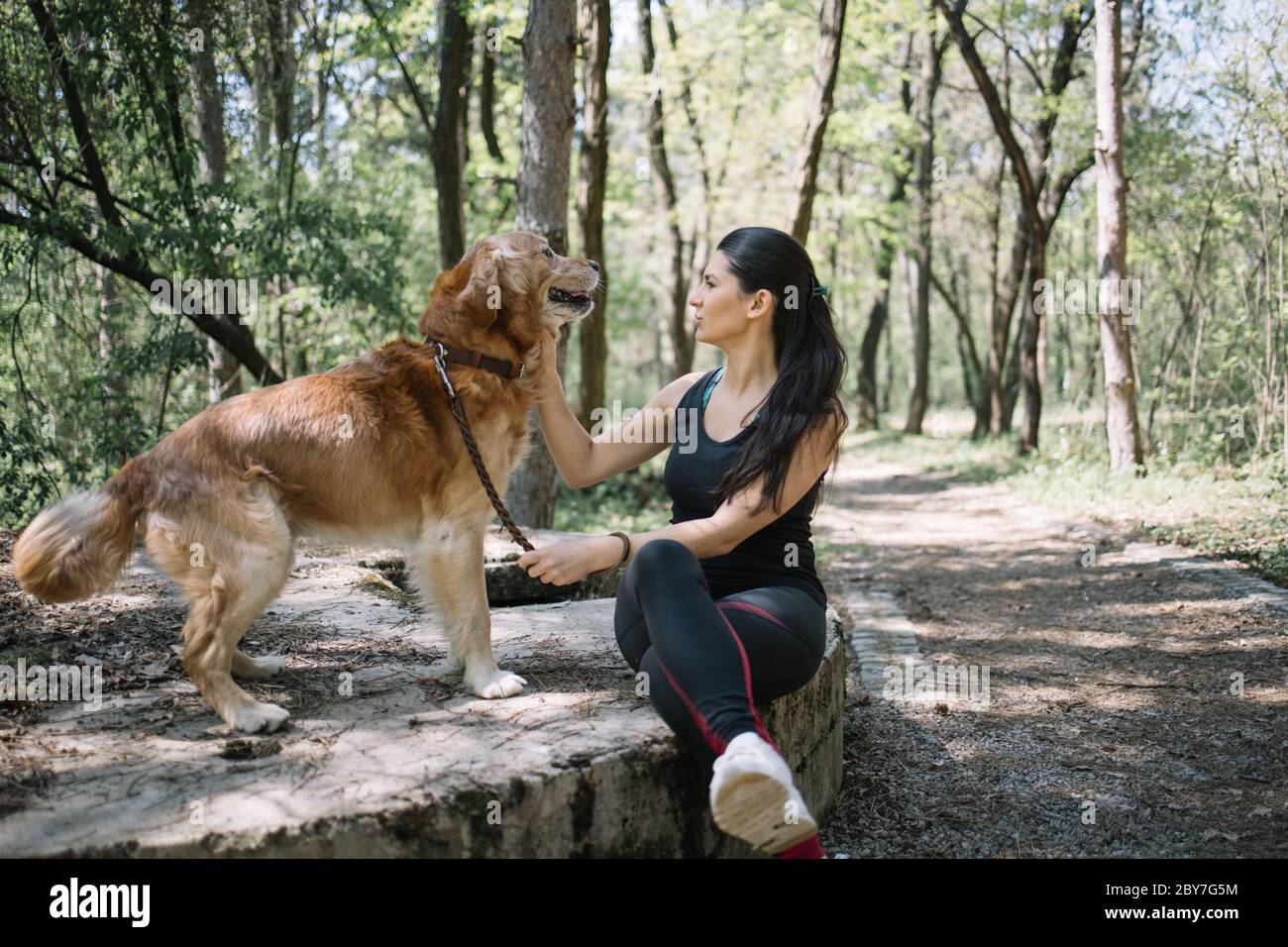 Girl sitting in nature and caressing her dog Stock Photo - Alamy