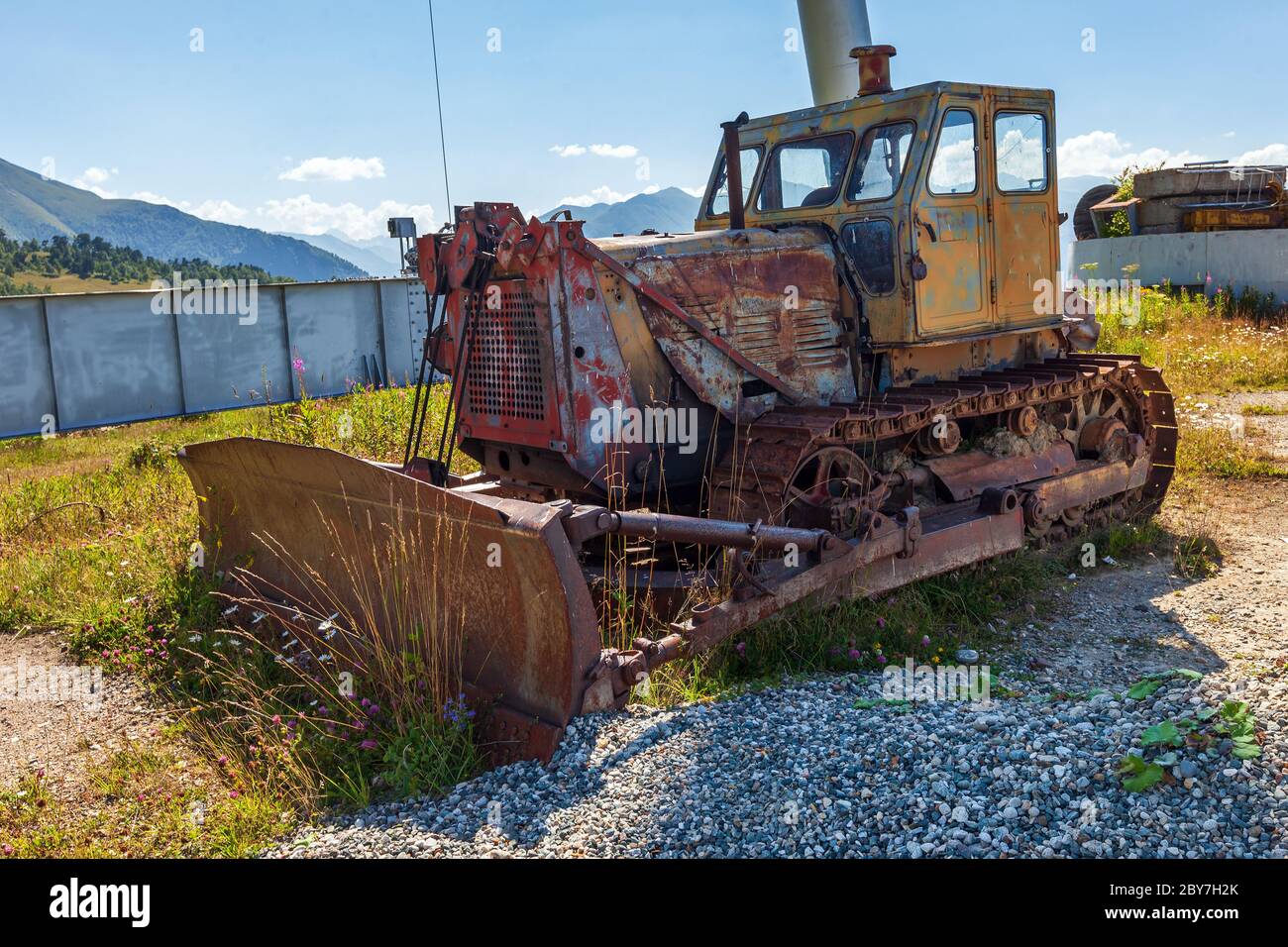 An old rusted tractor stands in the mountains, grass sprouted around it ...