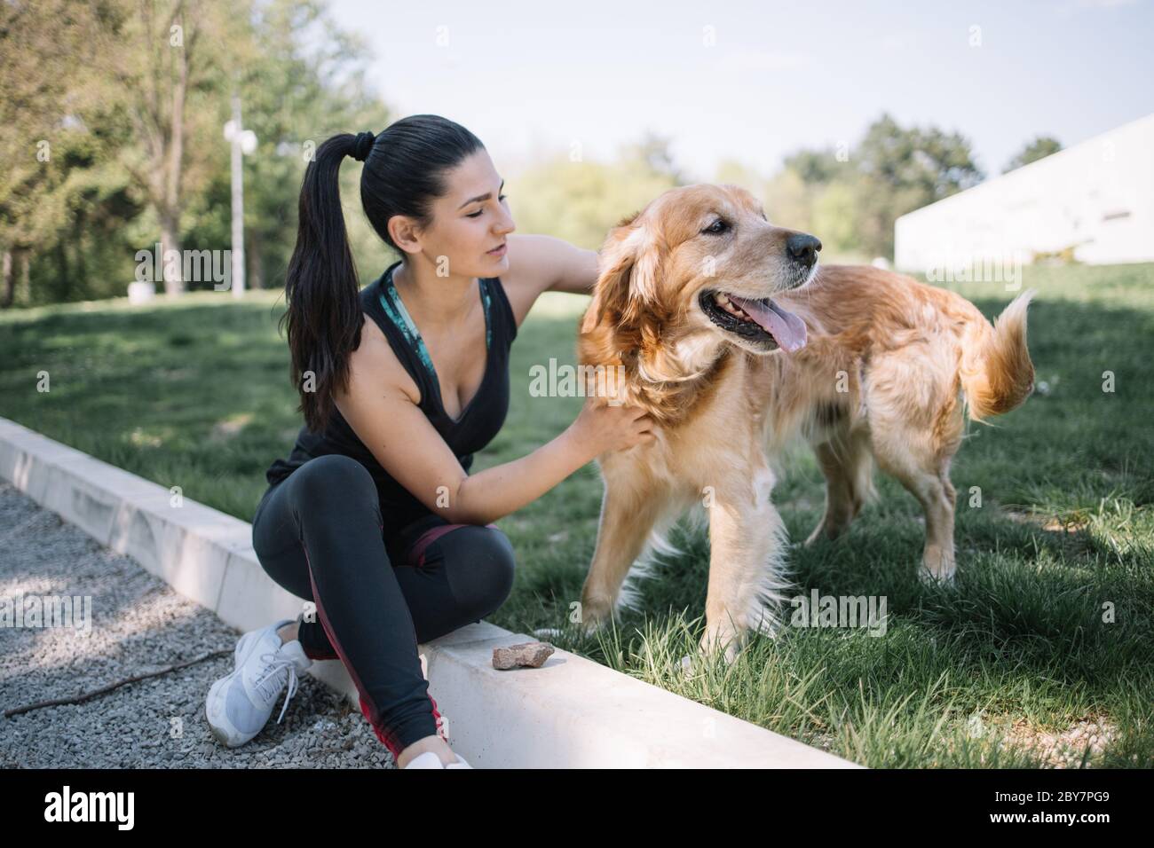 Woman sitting on ground cuddling her dog Stock Photo - Alamy