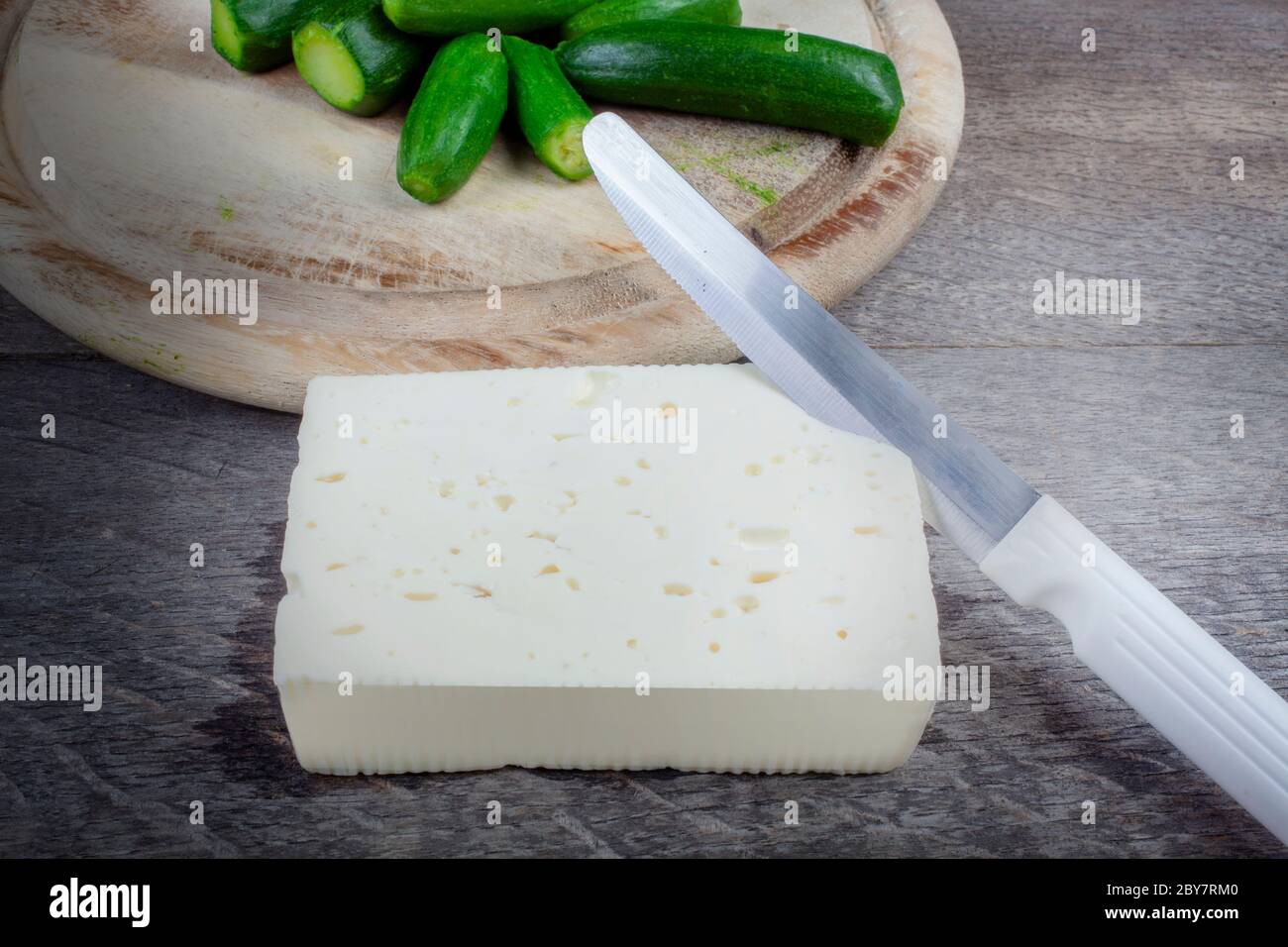 Studio Shot of Greek Cheese With Knife And Zucchini on Wooden Plate on ...