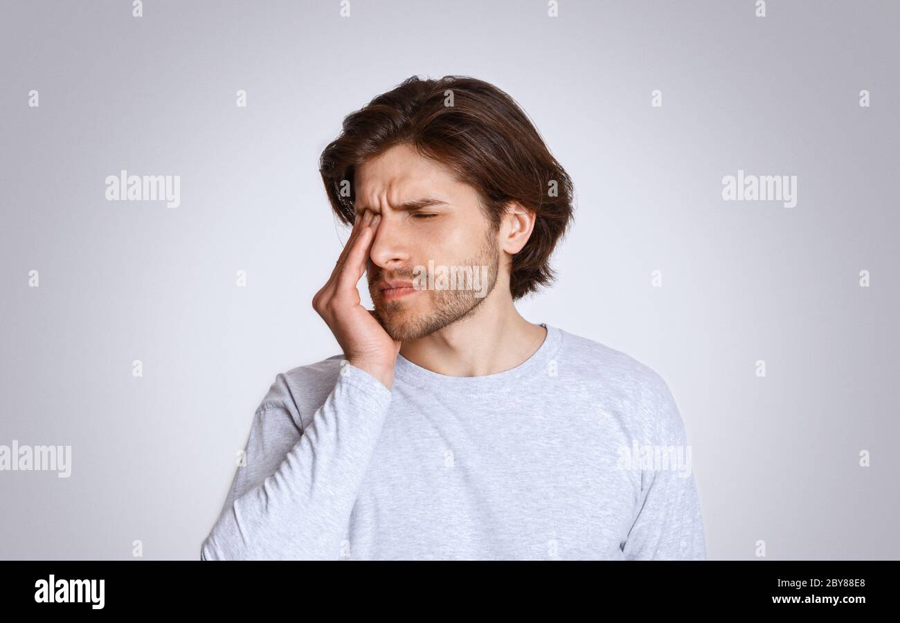 Feeling unwell. Guy feels pain in his closed eyes and presses hand ...