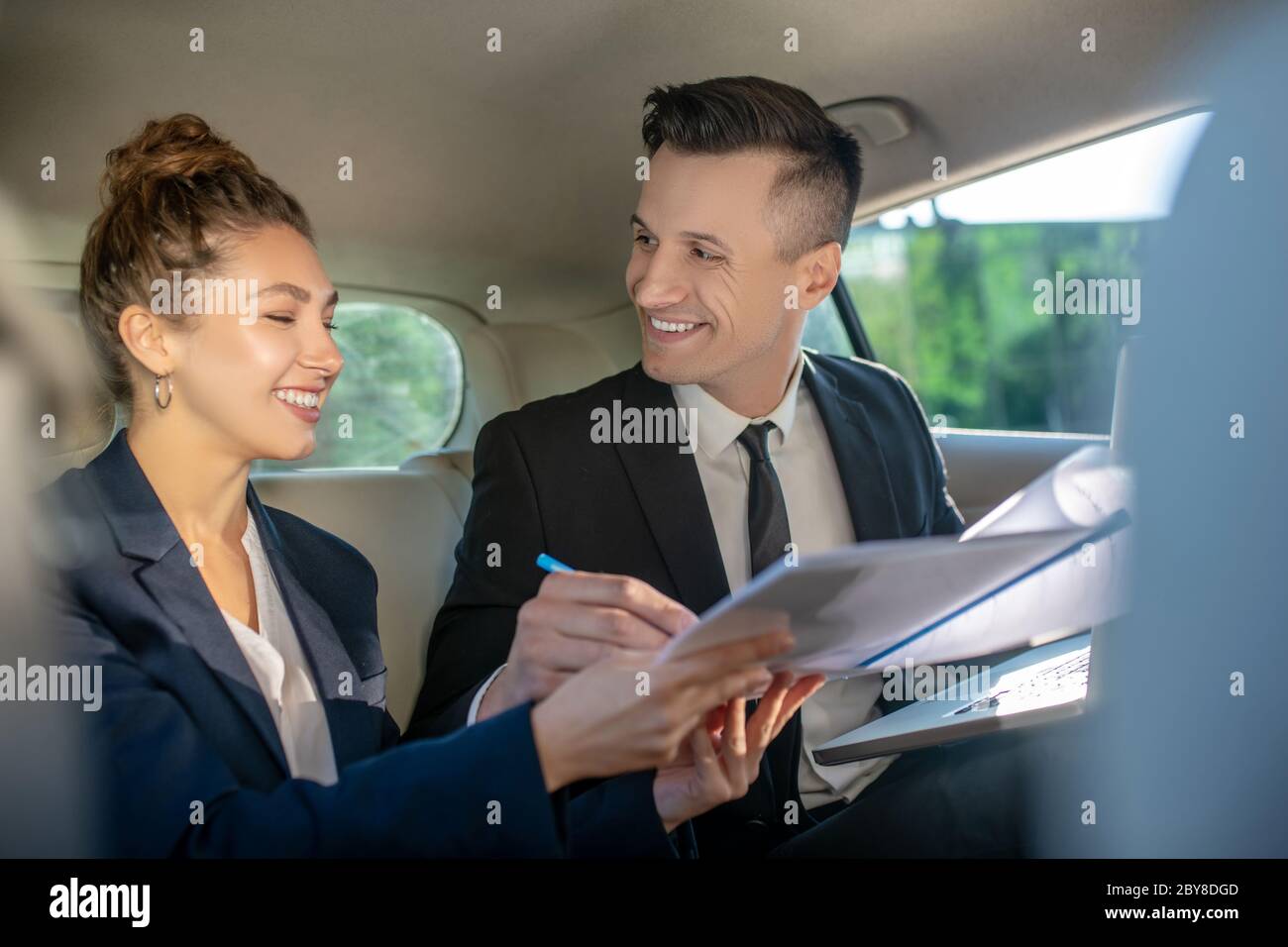 Happy man and woman signing document in car Stock Photo - Alamy